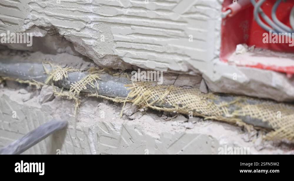 Plumber using a jackhammer to drill into wall, replaces old water pipes ...