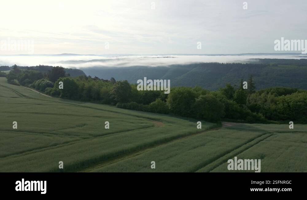 A steep and expansive river valley revealed behind lush, green farmland ...