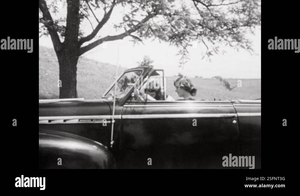 1950s: Two young women in a car come to a stop on a country road, the ...
