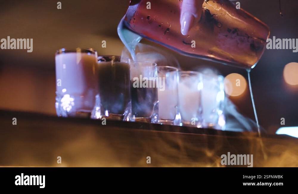 dry ice smoking shot glasses filling up with colorful cocktail (super ...