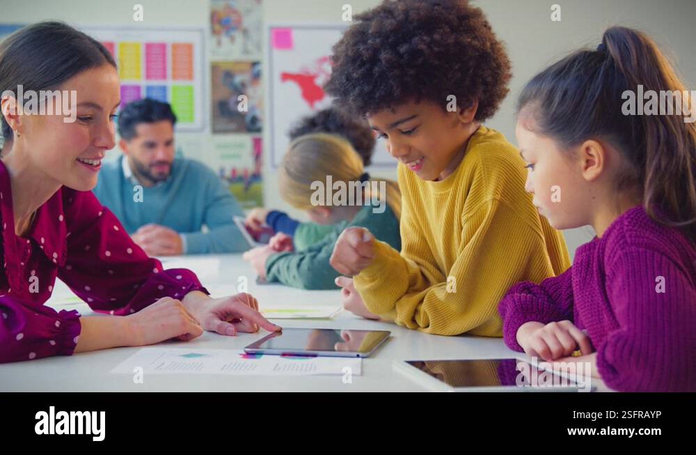 Elementary School Students And Female Teacher Using Digital Tablets In ...
