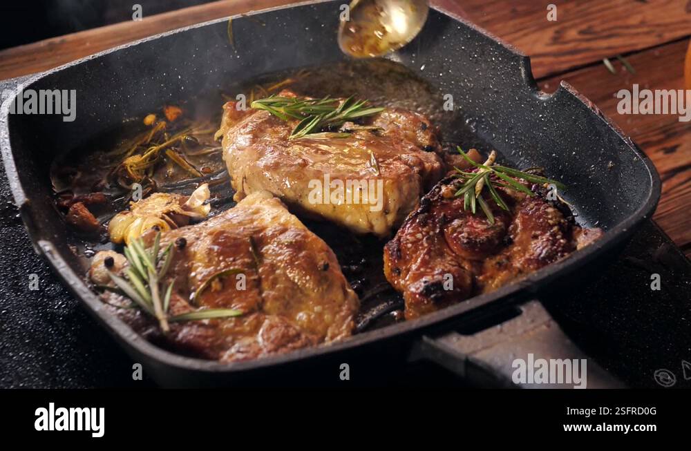 Meat steak is fried in oil and greased in a pan. The chef pours oil on ...