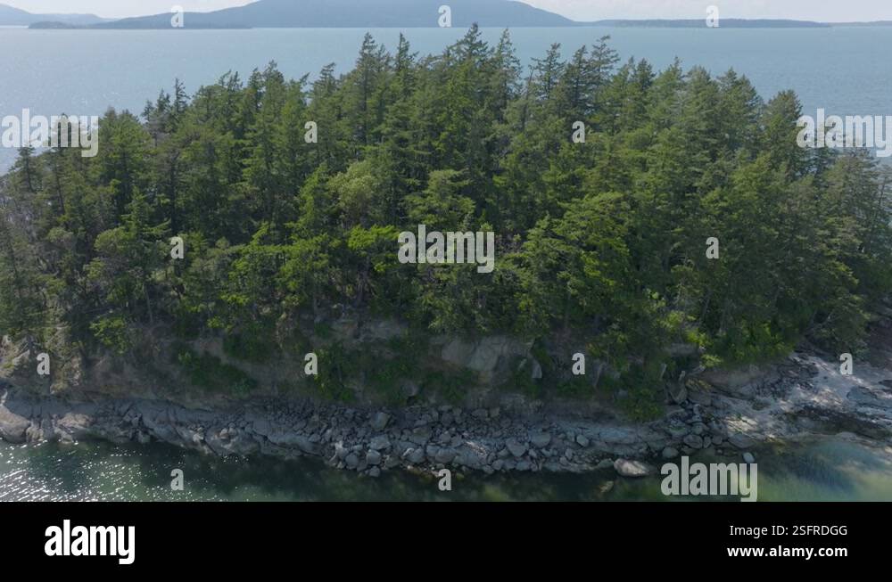 Aerial with boom up over beautiful tiny island in Puget Sound in an ...