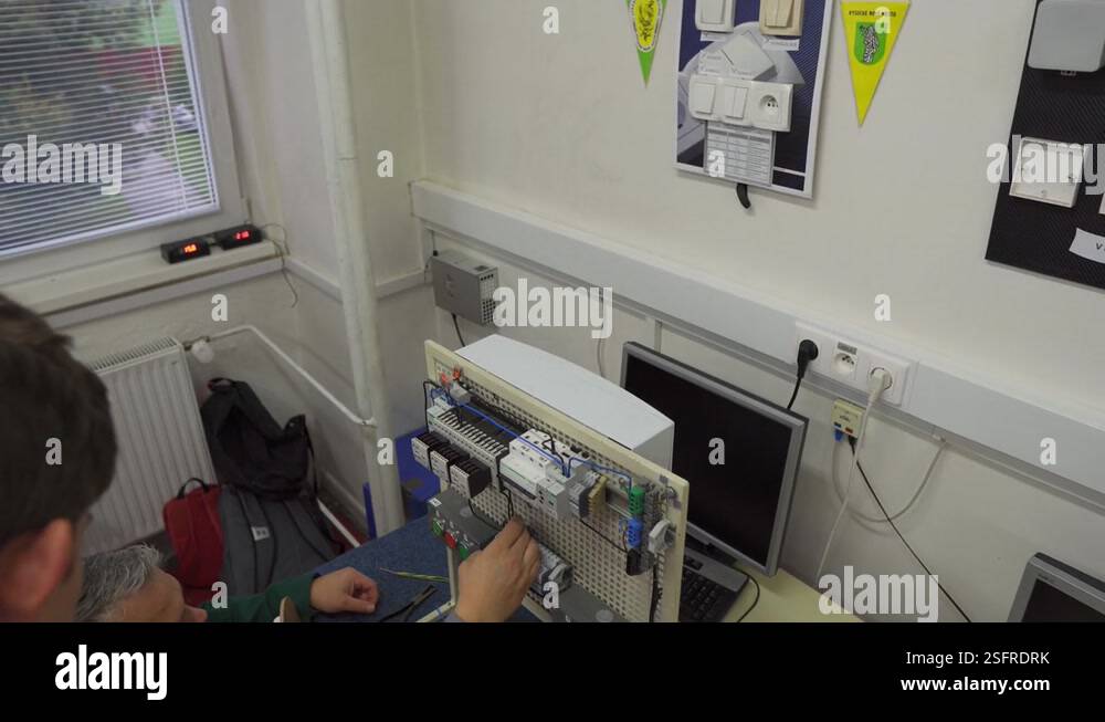 Adult male teacher helping a young student build an electrical switch ...