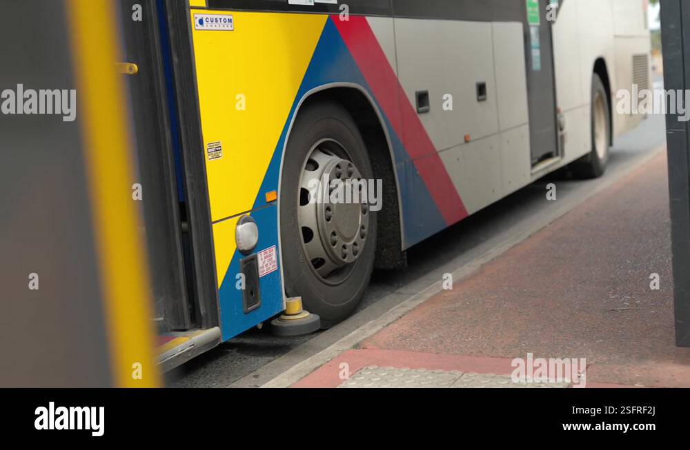 A busy bus interchange and bus stop with passengers boarding and ...