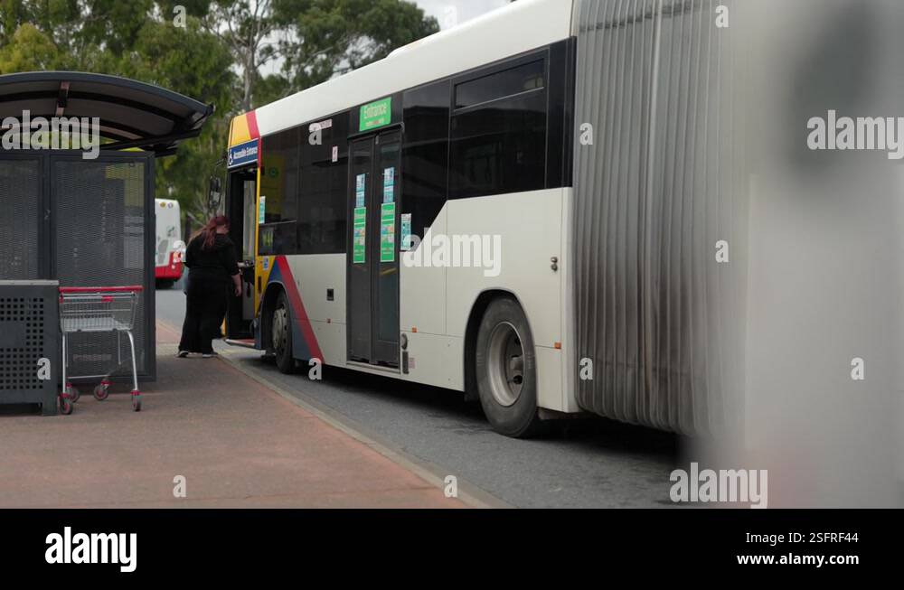A busy bus interchange and bus stop with passengers boarding and ...