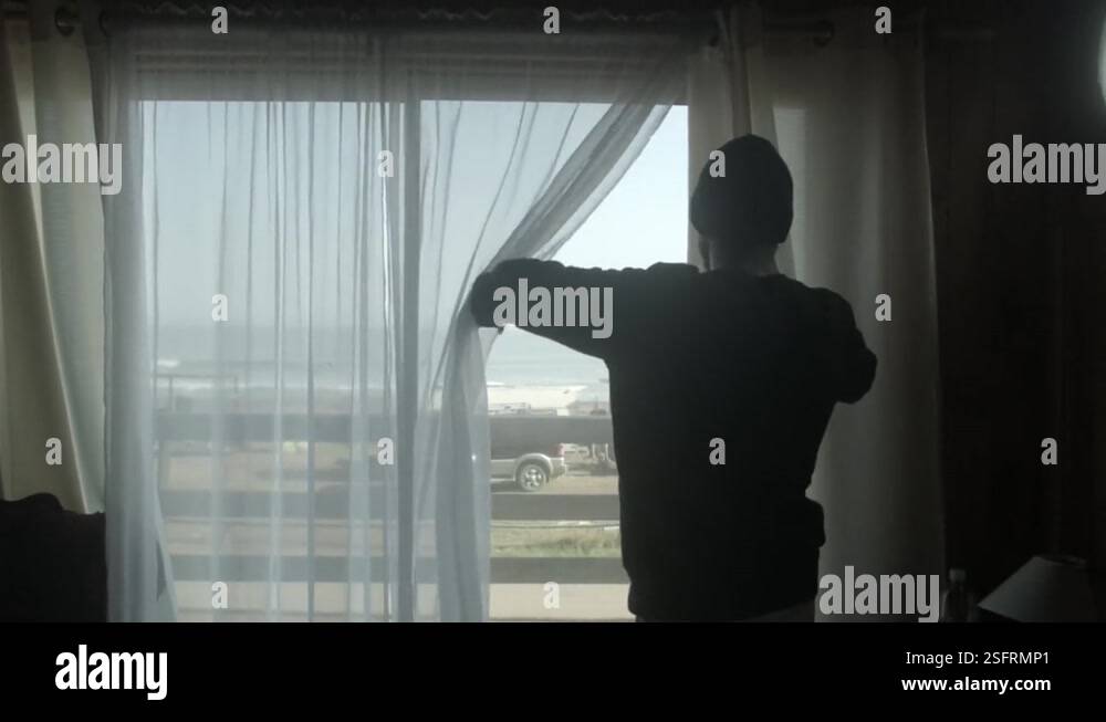 Man Wearing Bonnet Hat Push Aside The Curtain And Looks At The Glass ...