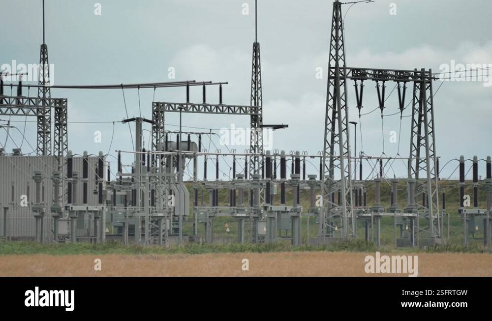 An electrical power plant in the farm fields. Slow-motion, pan left ...