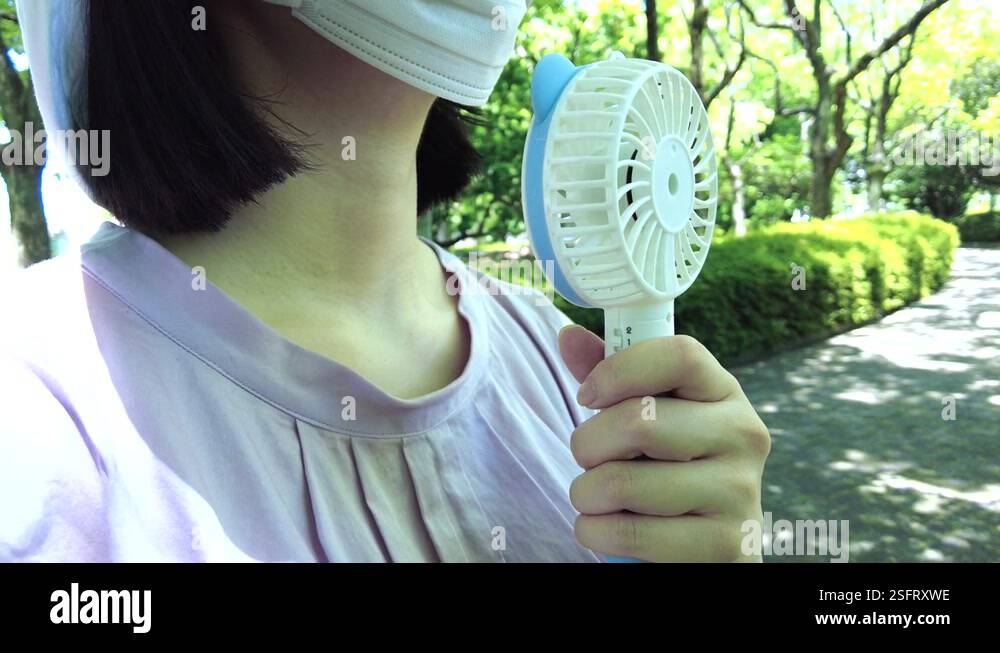 Woman with mask using the portable fan in the park, Japan. 4K Stock ...