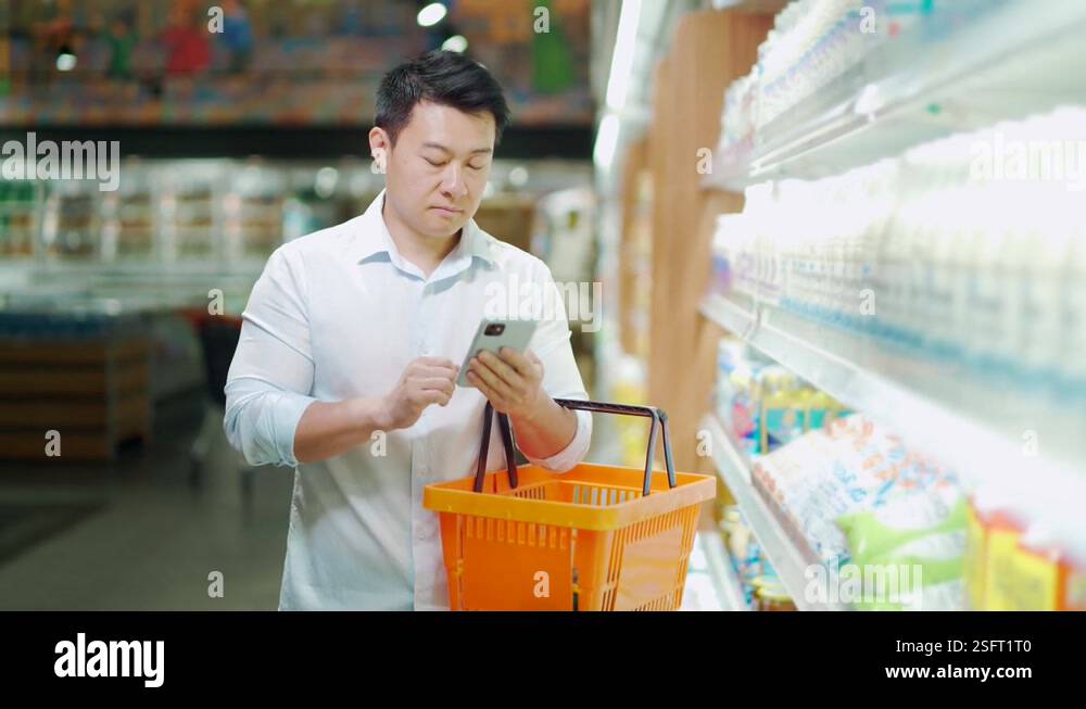 Asian male shopper pick in a grocery store is standing near the ...