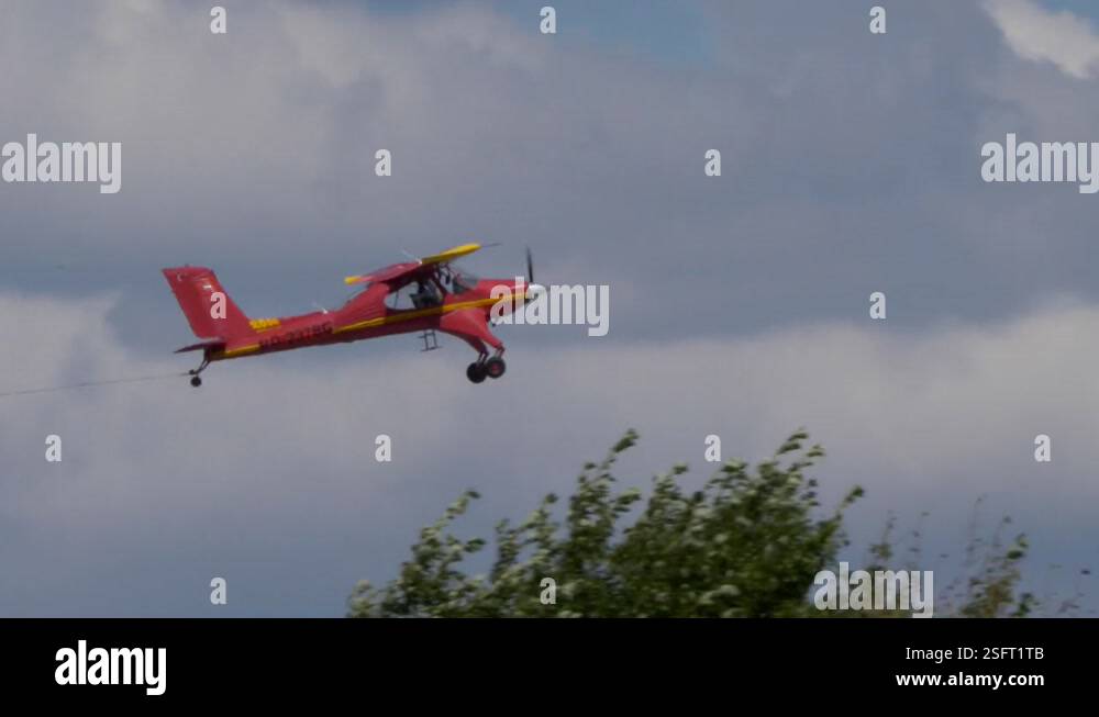 Red small sport plane flying in the sky pulls on a rope the glider ...