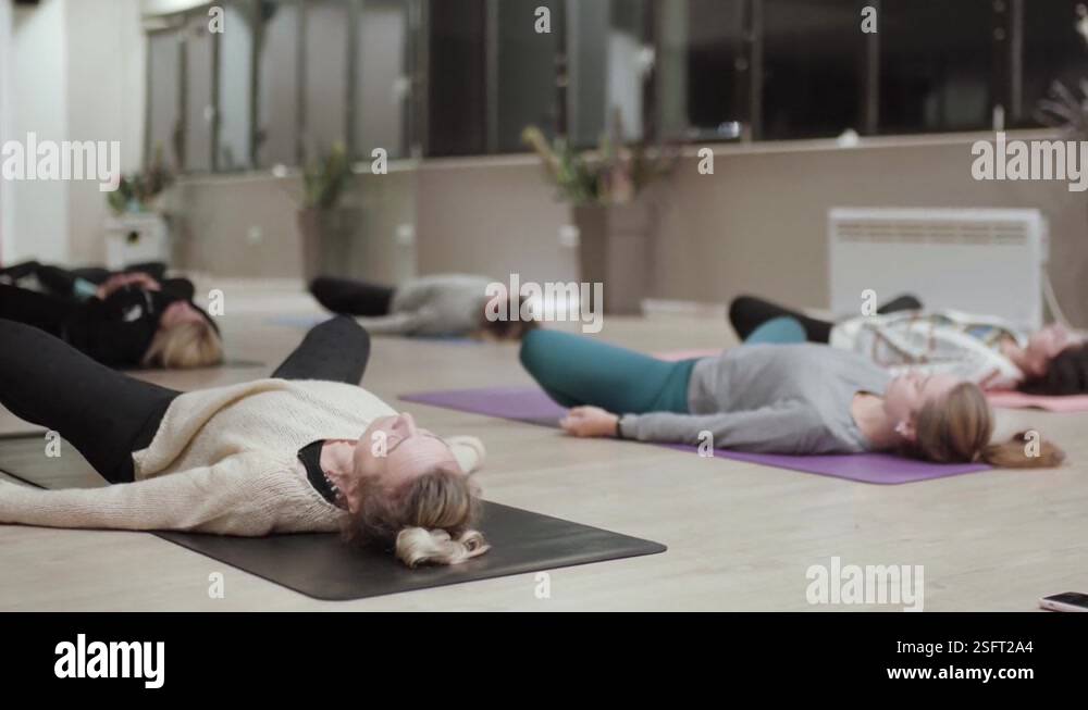 Students on yoga class. Lying on the ground meditating after streching ...