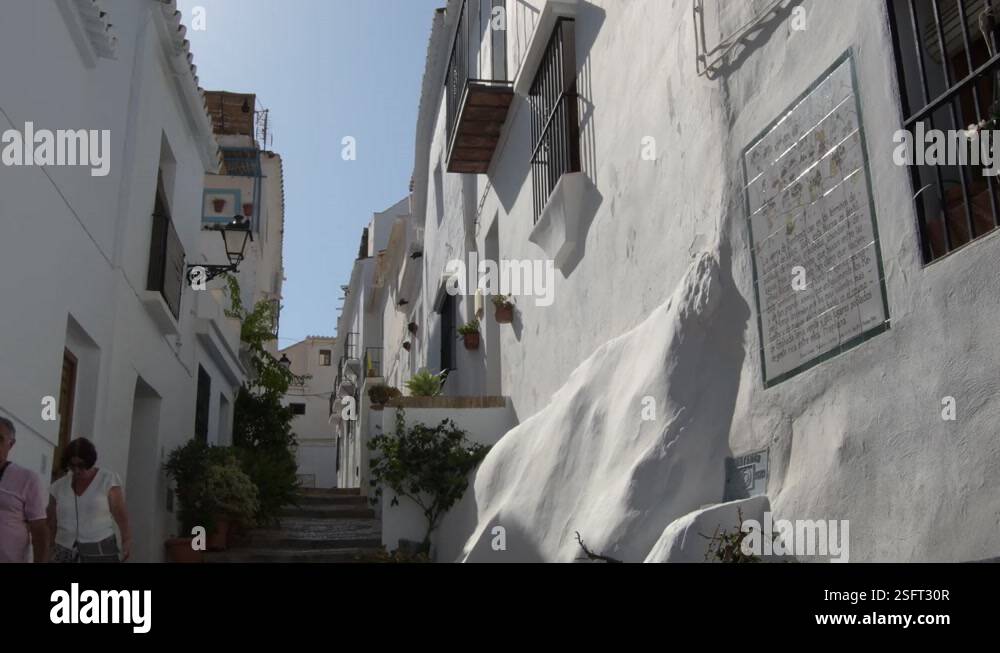People walking in a white andalusian street, Frigiliana, Spain Stock ...