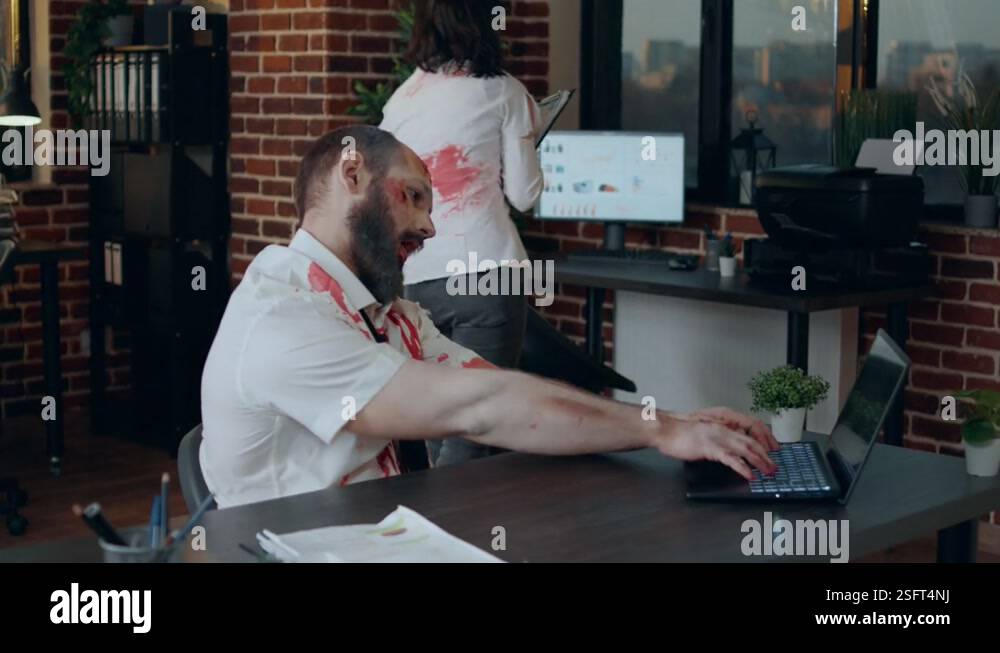 Scary office zombie with bloody wounds in workspace working on modern ...