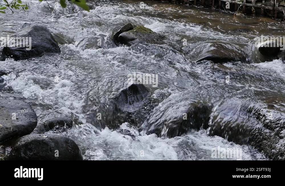 a mountain river with a fast flow of water and a rocky bottom rages and ...