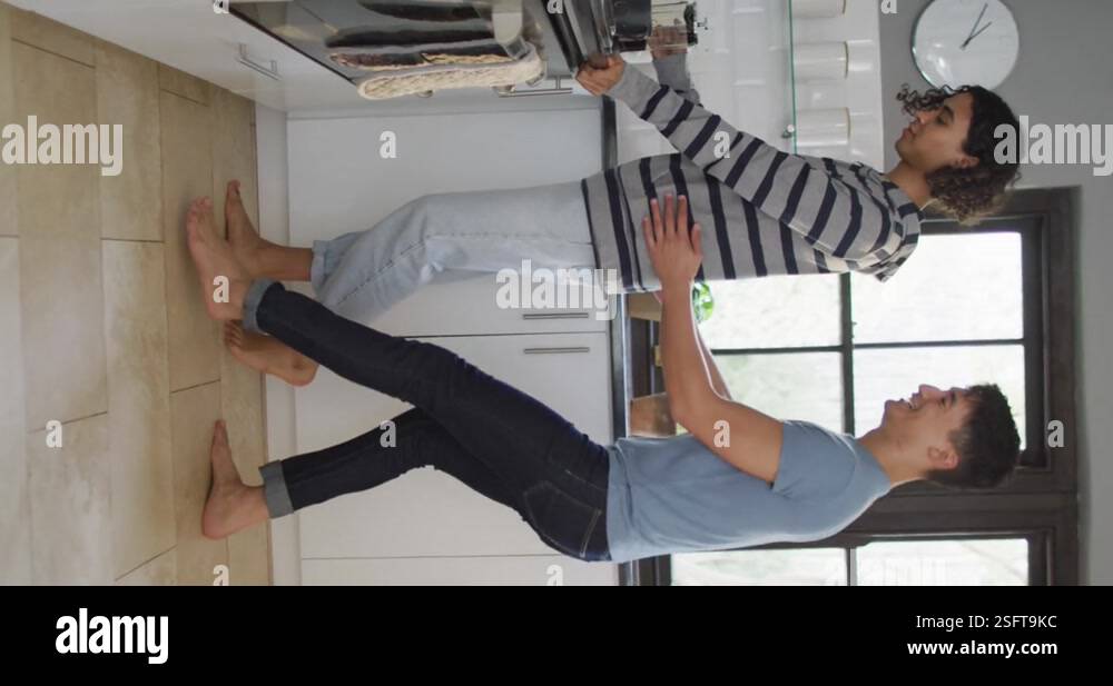 Vertical video of happy diverse couple drinking coffee and embracing in ...