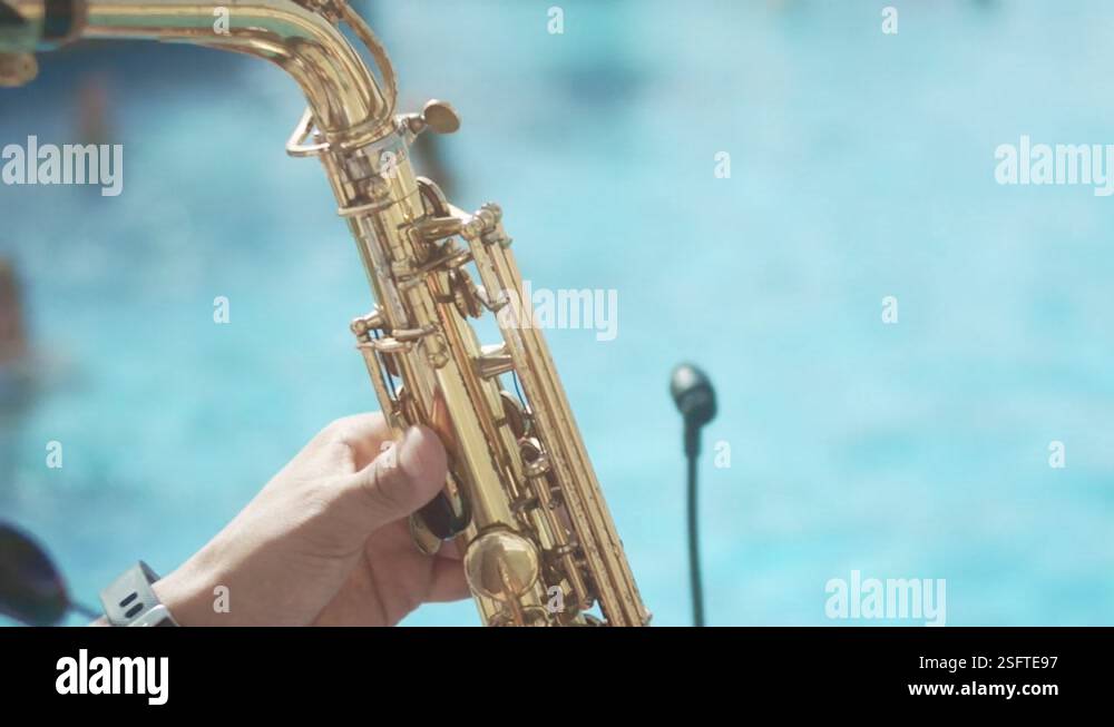 Male saxophonist plays the saxophone near the pool in the summer in a ...