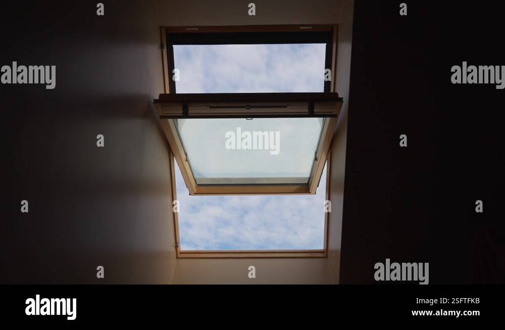 Time lapse of moving clouds seen through open dormer window on sloping ...