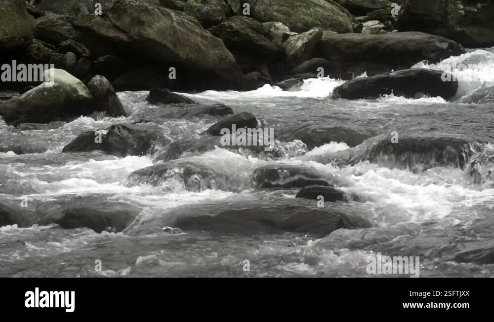 River with white water rapids breaking apart over large stones in river ...