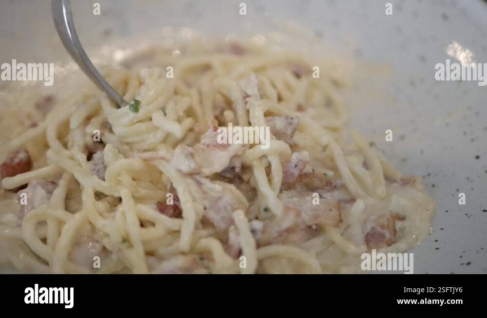 using fork to eat creamy carbonara spaghetti with fresh cheese and ...