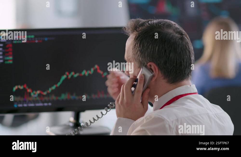 Back view of stock broker looking at computer monitor with graphs and ...