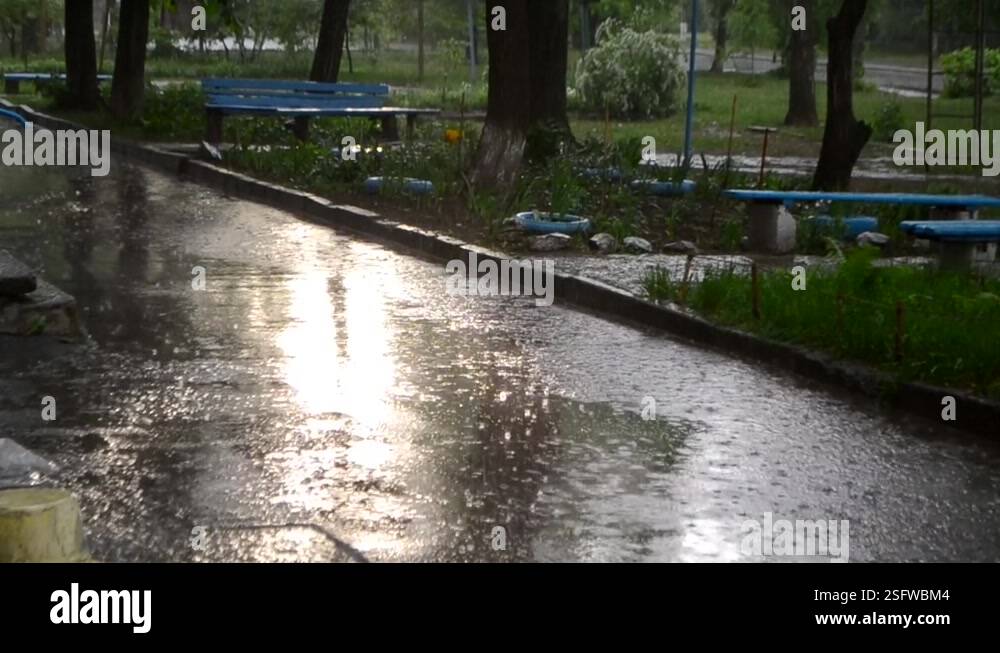 Heavy downpour rain is falling in city and the sun shining on summer ...
