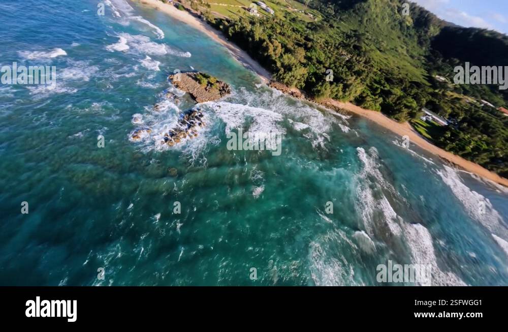 FPV drone shot around a small rocky island and over a beach in sunny ...