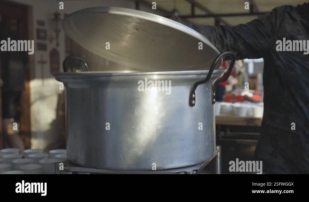 A slow motion shot of a pot of soup which is being opened by a person ...