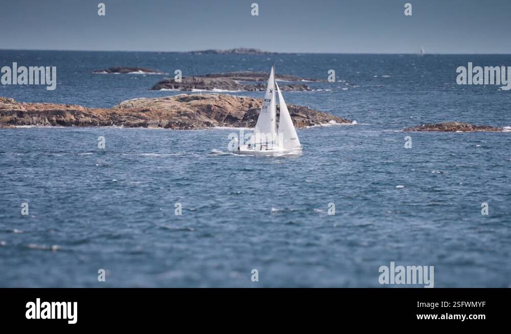 A small sailboat battling the waves between the rocky islands Stock ...