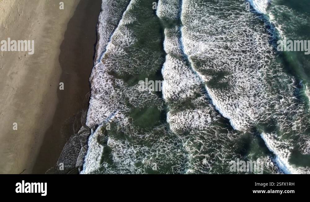 Drone shot. Zoom out of birds eye view of waves rolling in on a beach ...
