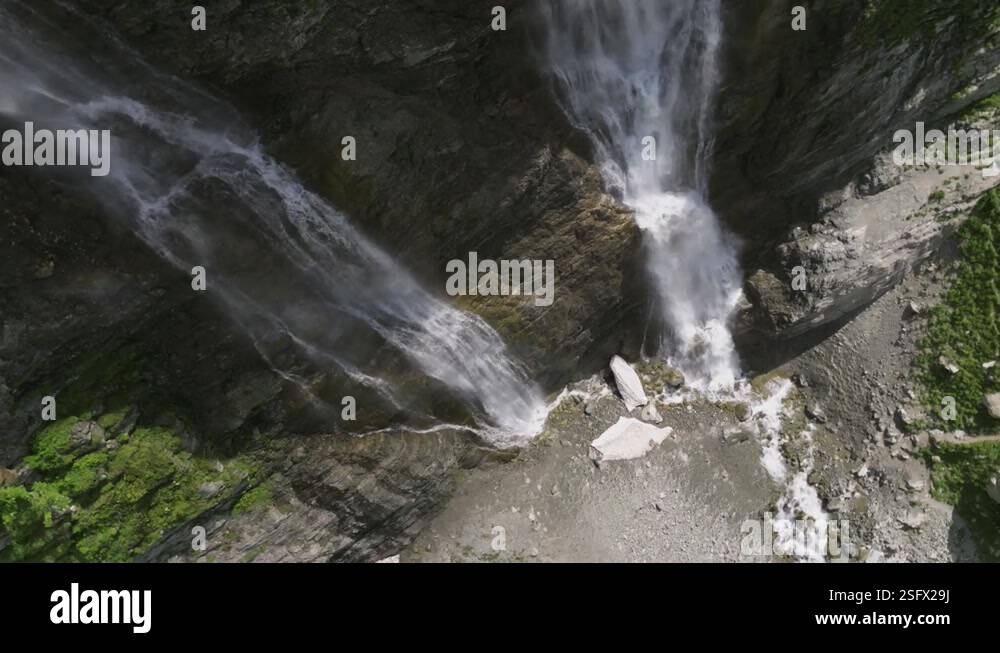 Aerial view of a glacial waterfall high in the mountains on a sunny day ...