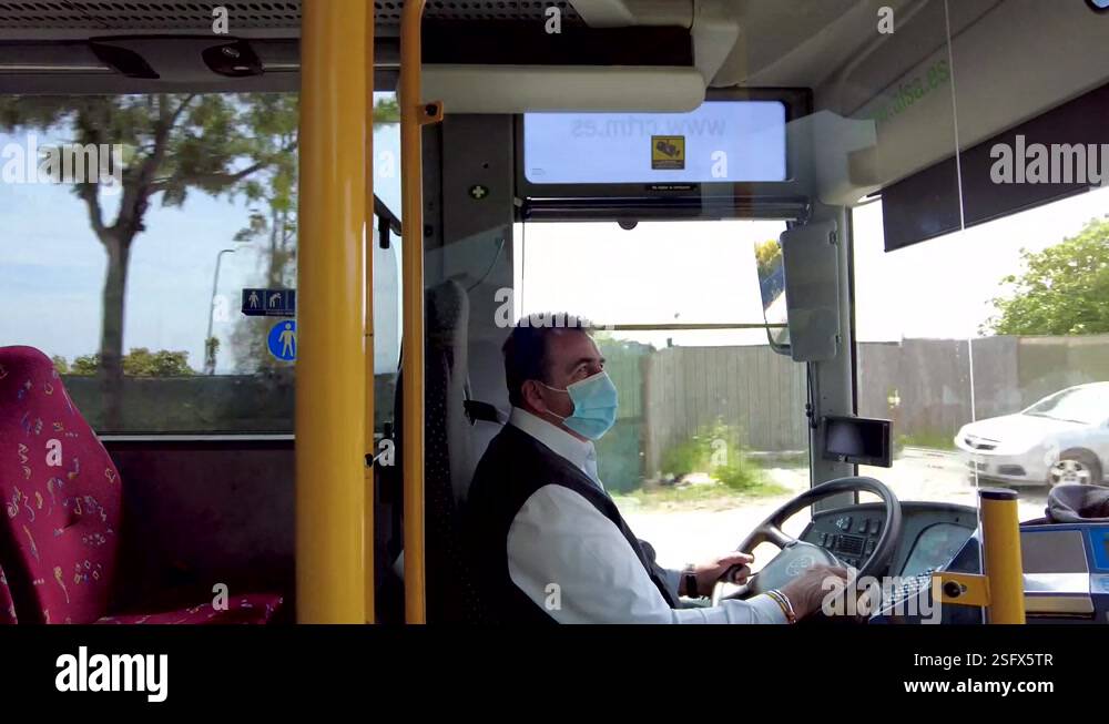 A Spanish bus driver is wearing a blue-colored face mask at work. The ...