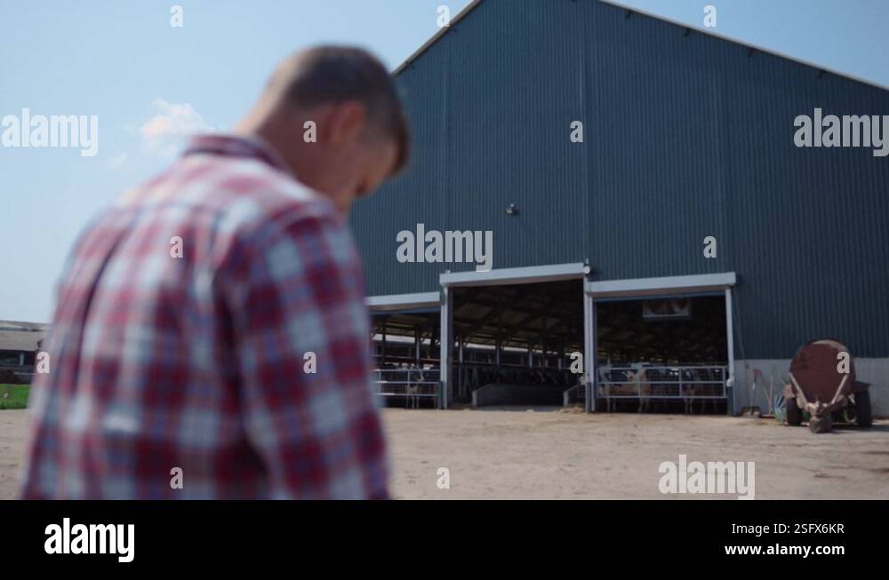 Farm worker sitting outside barn on farmland ranch close up. Farmer ...