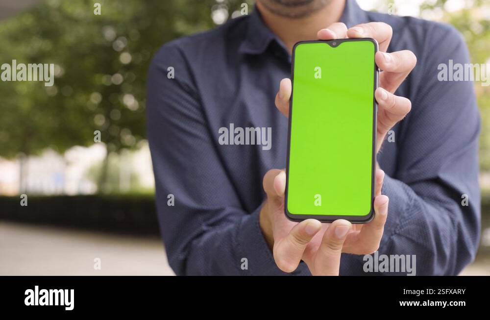A man shows a smartphone (vertical) with green screen to the camera in ...