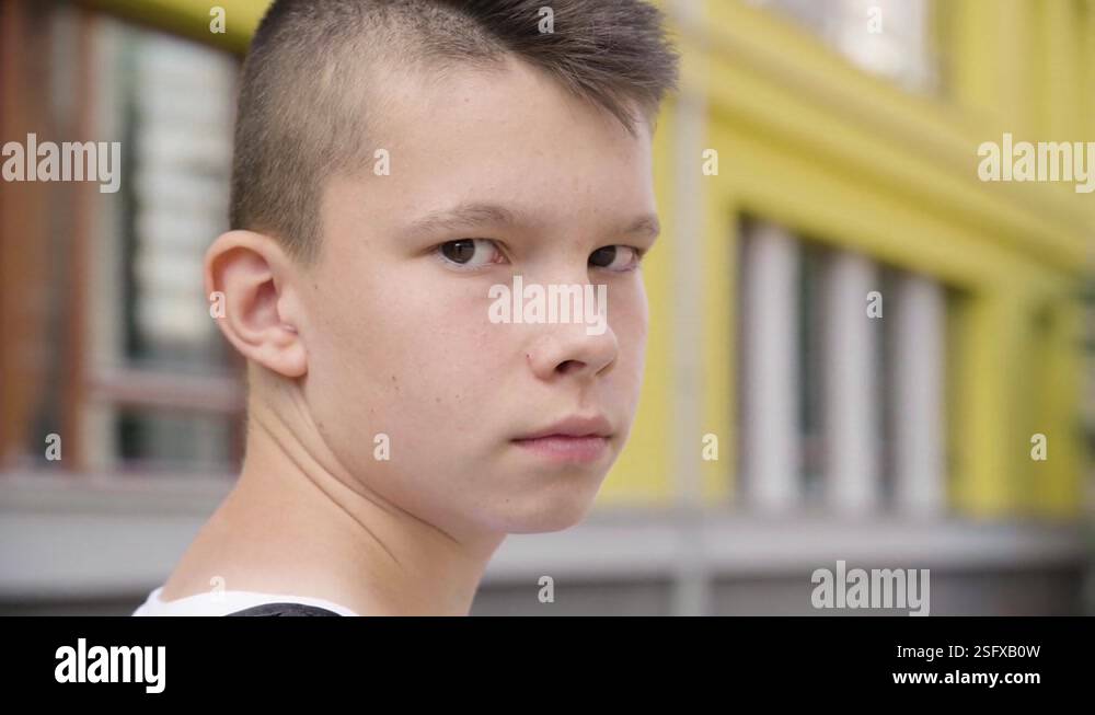 A Caucasian teenage boy looks over his shoulder at the camera - closeup ...