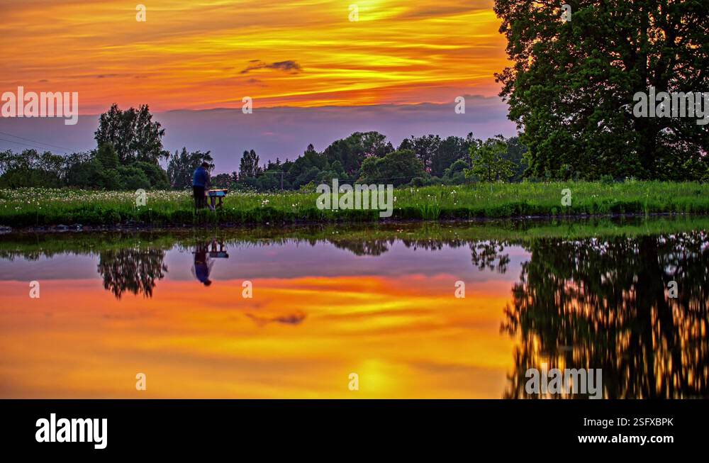 Symmetry in lake reflection of the amazing orange sky and rural area ...