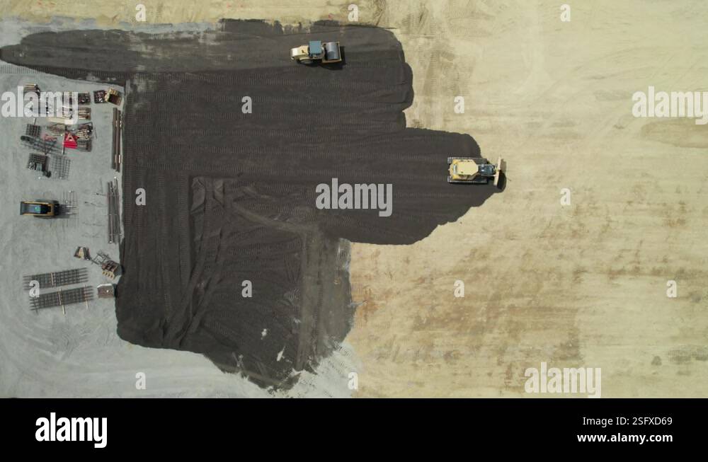 Aerial view of yellow tracked tractor rakes the ground to build an ...