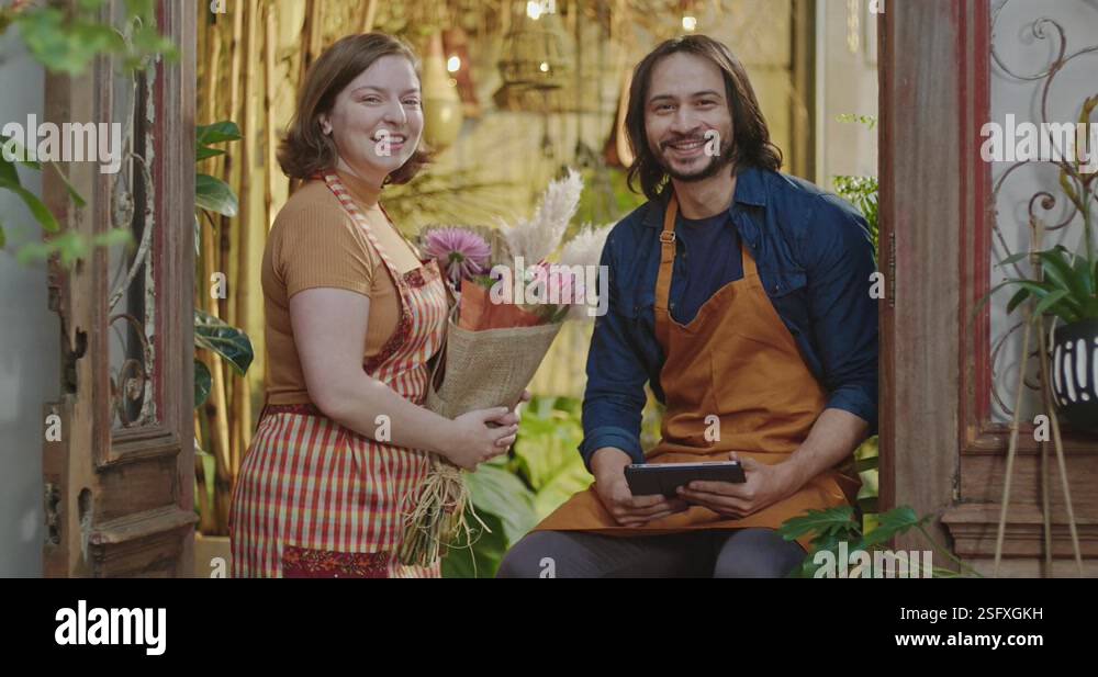 Portrait of two young staff of local retail store looking at camera ...