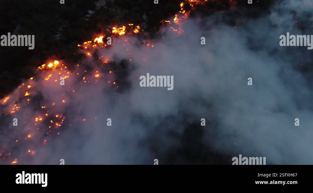 Aerial panoramic view of a forest fire at night, heavy smoke causes air ...