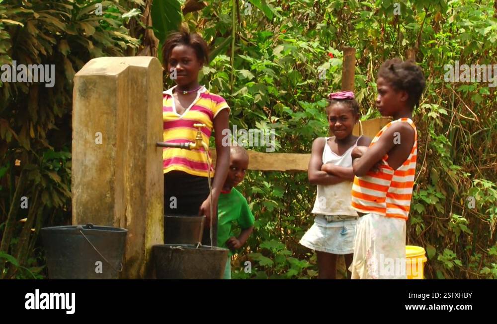 Girls from a village fetching water from a public source in buckets ...