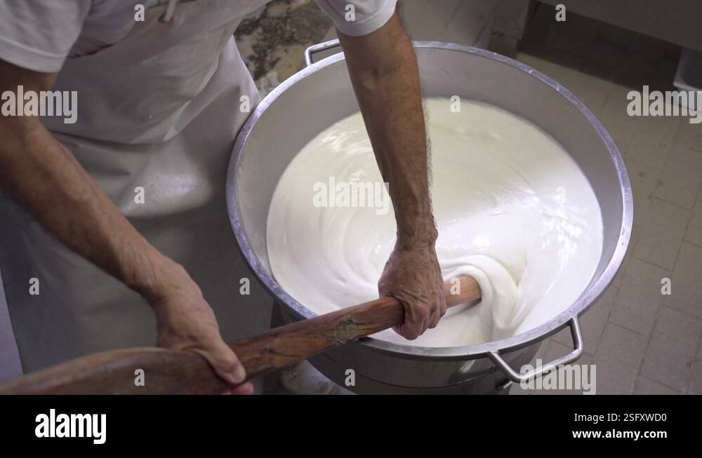 Male worker string mozzarella cheese in factory during process - slow ...