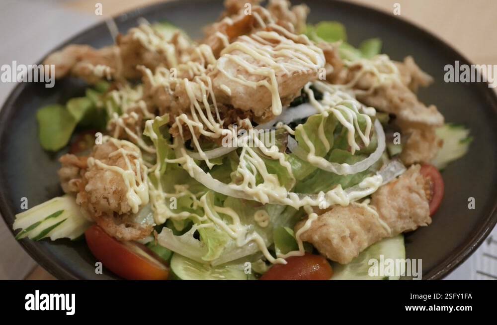 rotating view of a bowl of salad full with vegetable and fried crab ...