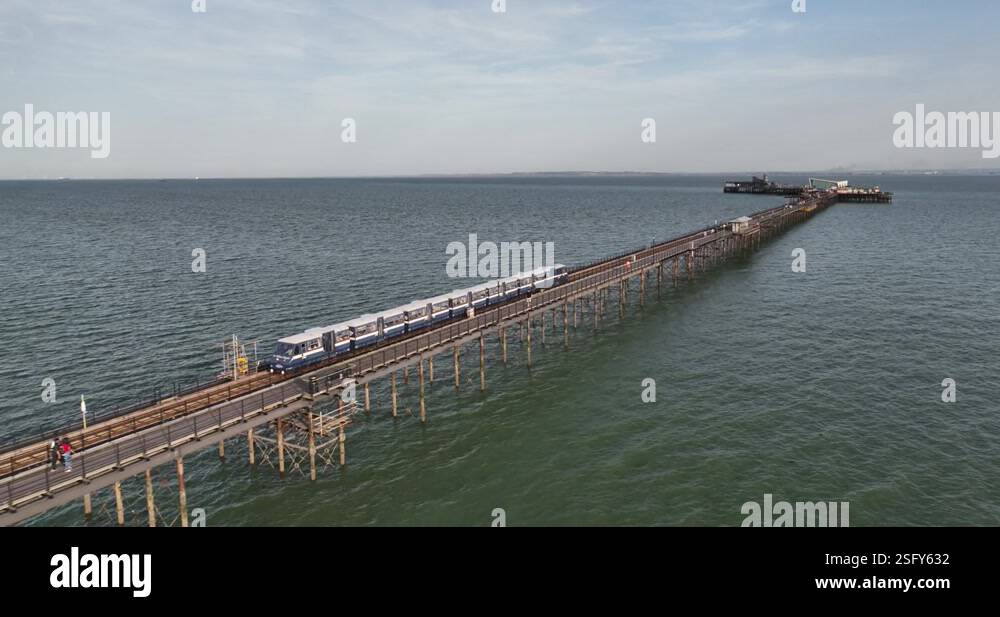 Tourist walking on long pier along with train driving on Southend Pier ...