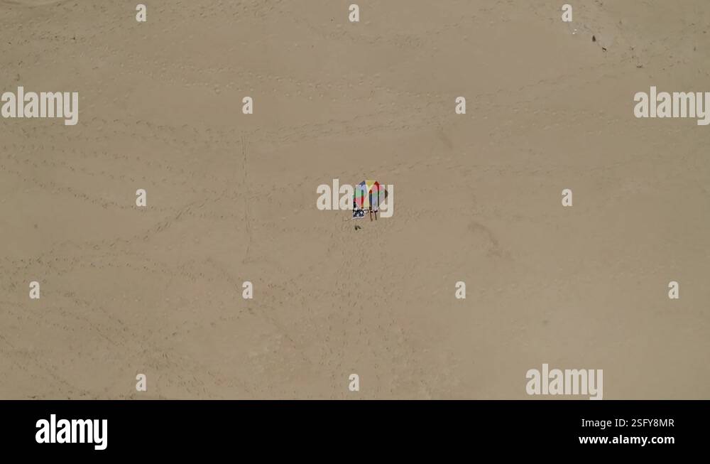 descending drone flight to the beach and a sunbathing person under a ...