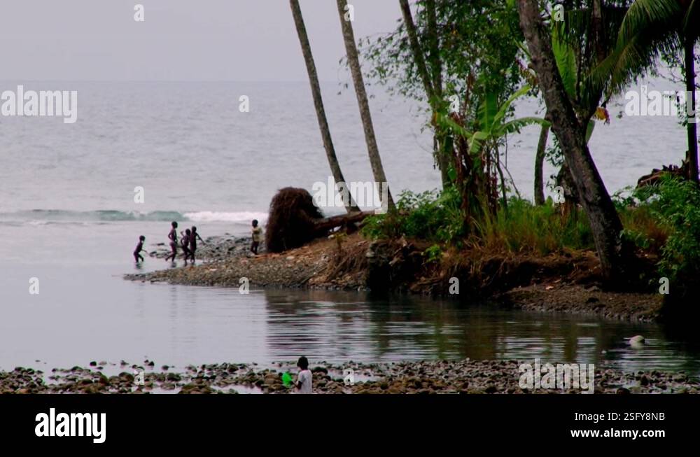 Group of silhouetted children play in the Atlantic Ocean on the beach ...