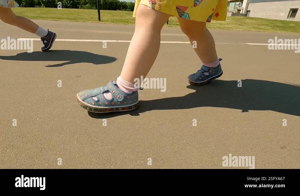 Cute female baby kid legs in sandals going on asphalt road steadicam ...