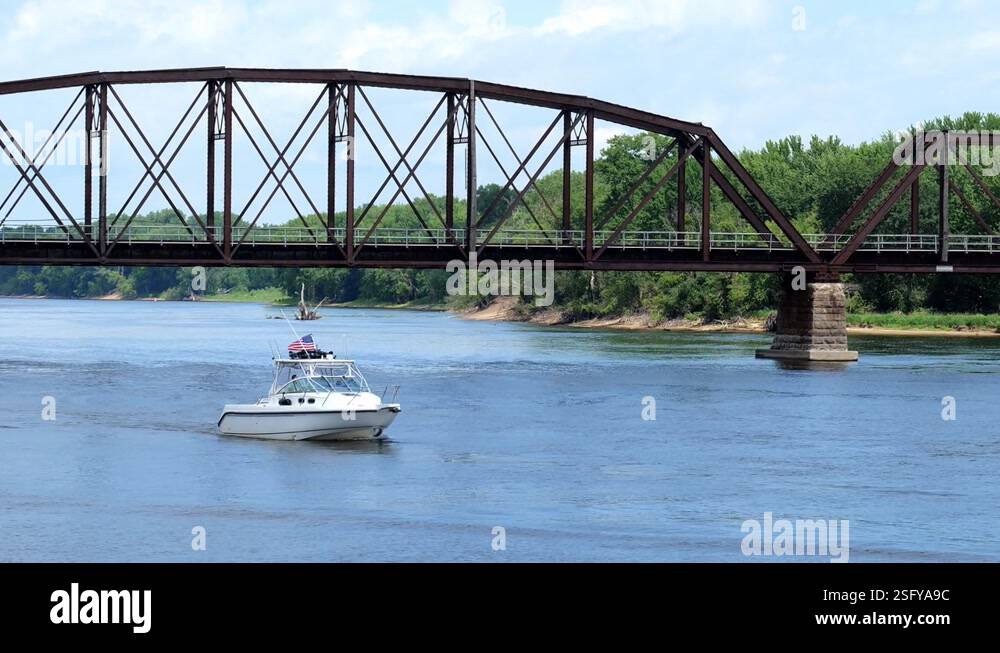 White boat on the Mississippi River cruises under a railroad bridge ...