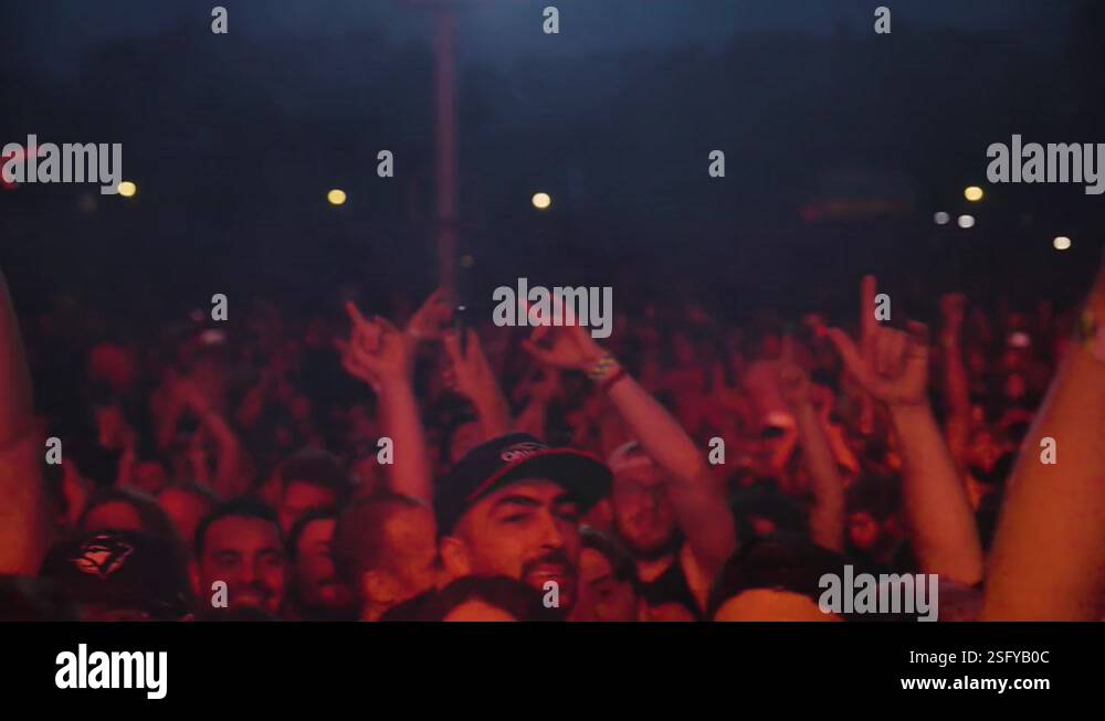 Crowd of people dancing at a rock music festival with rock on hand ...