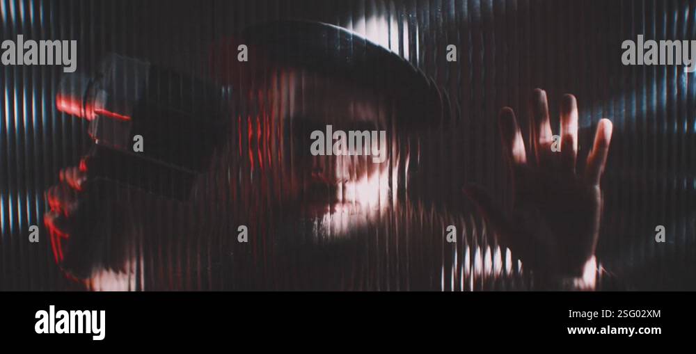 Man in shutter lights looking through clear panel with vintage camera ...