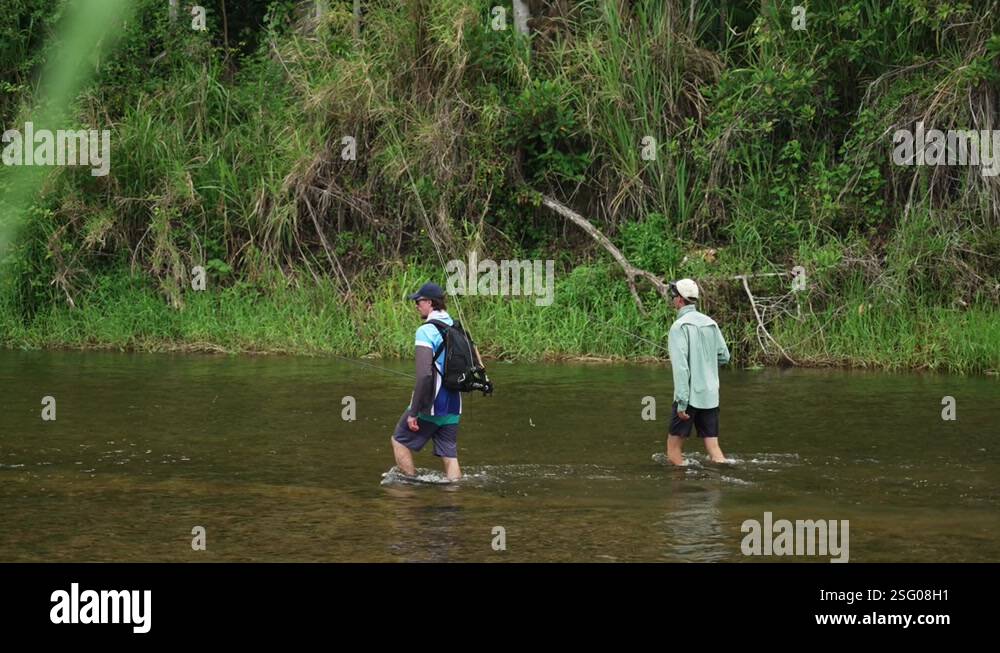 Pair Of Fishermen Wading Through Australian Creek Water With Fishing ...